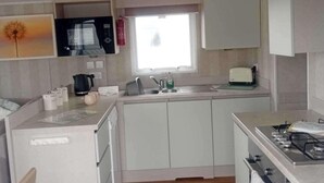 Uma cozinha compacta com micro-ondas, torradeira, pia e fogão.