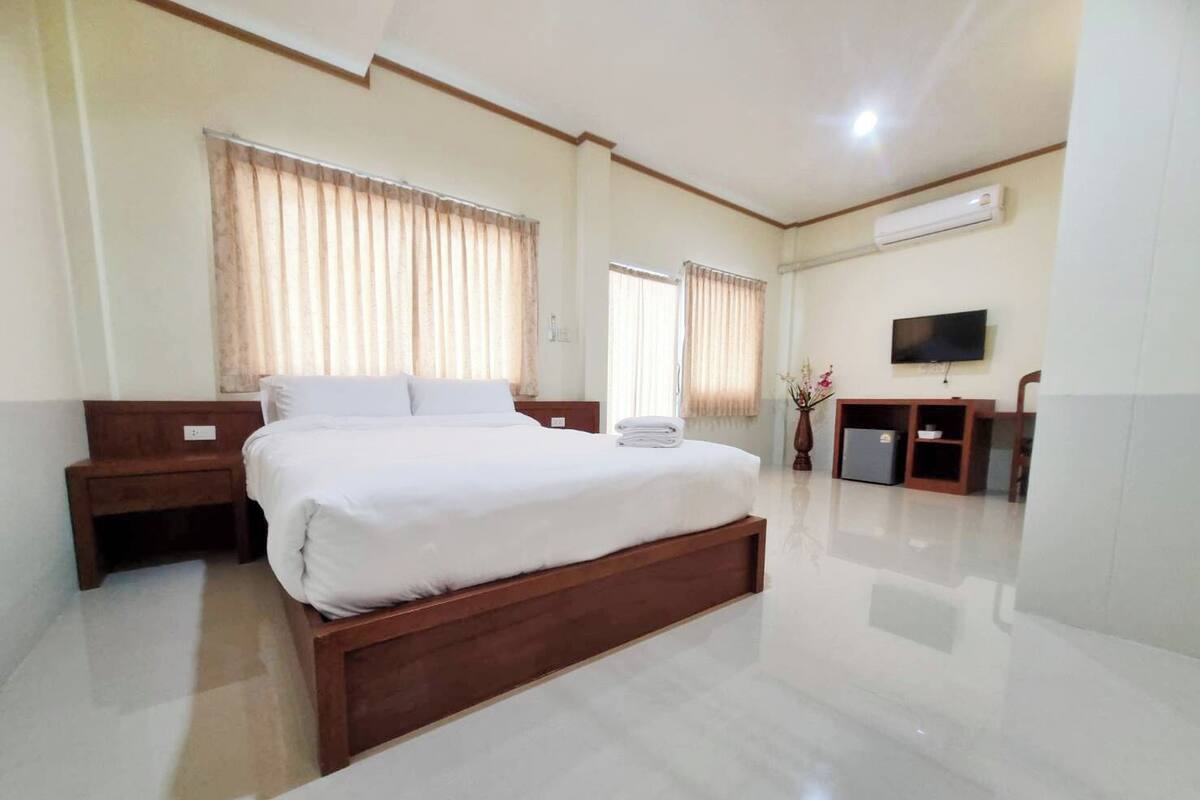 Quarto de hotel com uma cama grande, televisão, escrivaninha e uma cadeira.