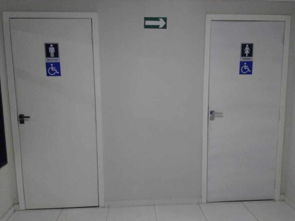 Duas portas com placas de acessibilidade para cadeirantes e um sinal de seta acima.