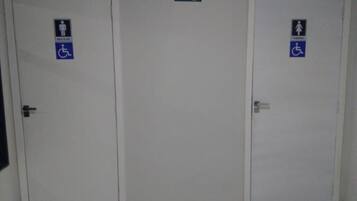 Duas portas com placas de acessibilidade para cadeirantes e um sinal de seta acima.