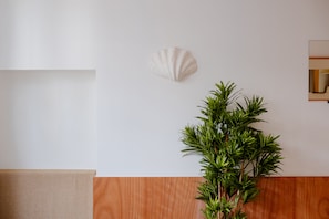 Um quarto com parede de madeira, parede branca com decoração de conchas e uma planta verde.