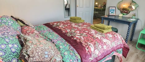 Quarto com cama, escrivaninha, cadeira e espelho.
