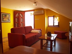Uma sala de estar com um sofá vermelho, uma mesa de centro de madeira e uma televisão.