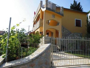Um edifício de dois andares com fachada de pedra, varanda e entrada protegida por grades.