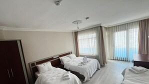 Quarto de hotel com duas camas, um guarda-roupa e uma janela com cortinas.