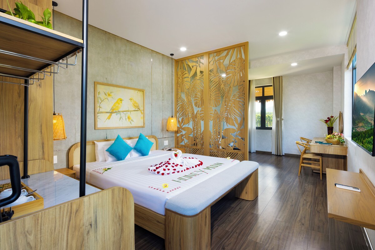 Quarto de hotel moderno com uma cama grande, uma escrivaninha e vista para uma paisagem montanhosa.
