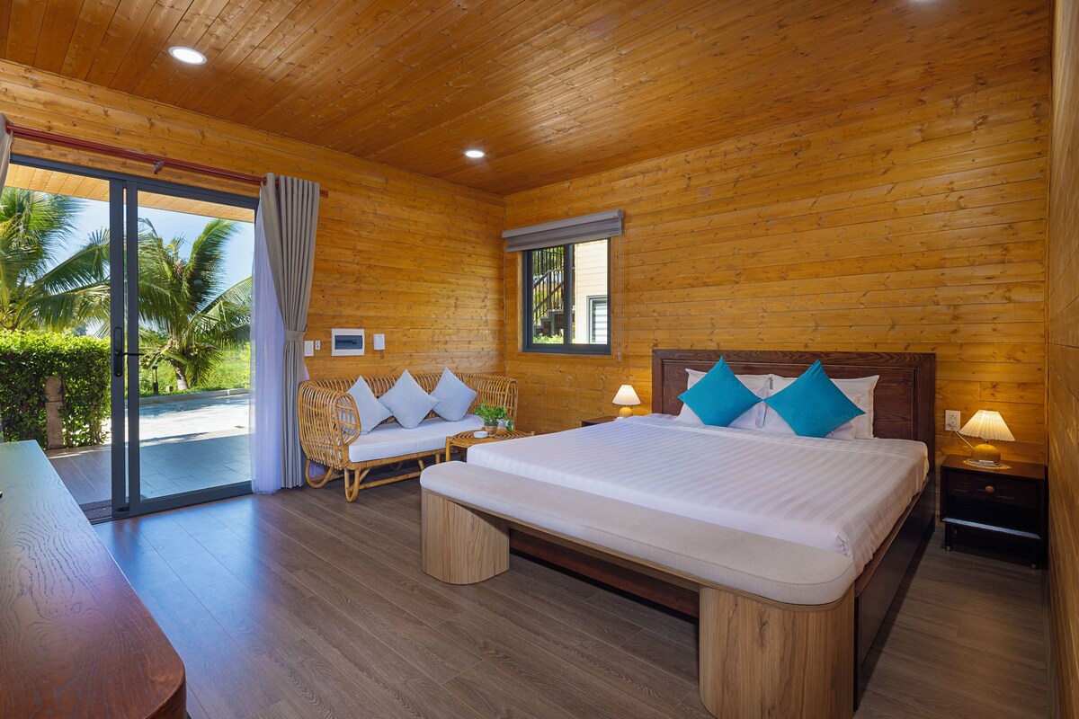 Quarto com piso de madeira, uma cama, um sofá e uma mesa.