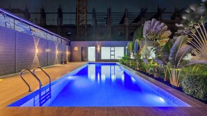 Piscina interna com vista clara da borda, um conjunto de degraus que levam à água e área circundante com parede de tijolos e plantas em vasos.