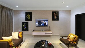 Uma sala de estar com televisão de tela plana, um sofá, uma mesa de centro e uma poltrona.