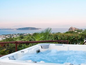 Uma banheira de hidromassagem com vista para o mar e uma montanha ao longe.