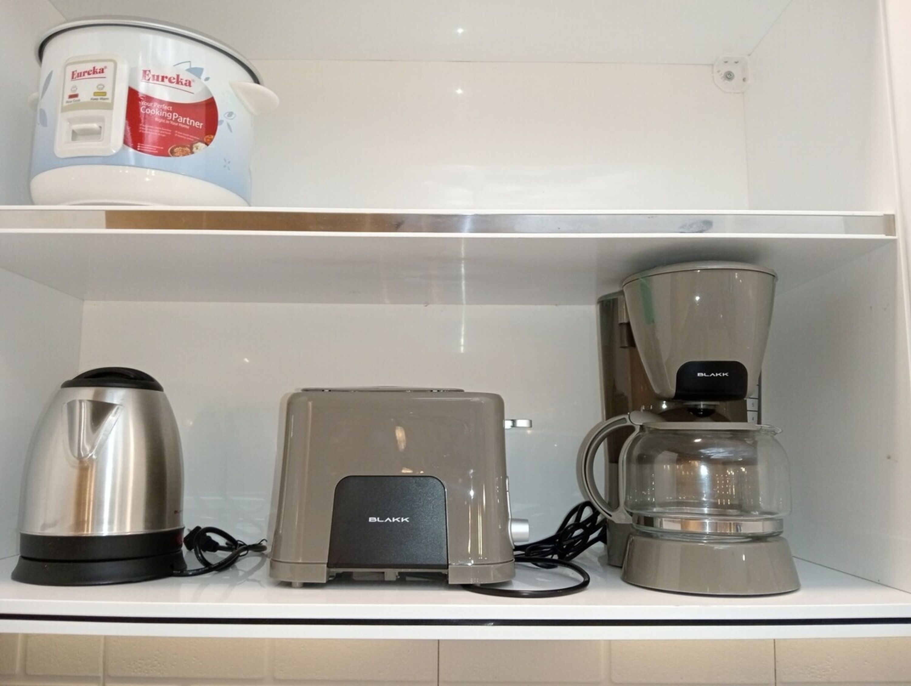 Uma cozinha com uma cafeteira, um liquidificador e um recipiente com óleo de cozinha na bancada.
