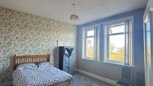 Quarto com cama, cadeira, guarda-roupa e janela com vista.