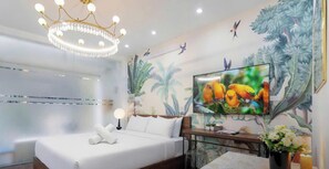 Quarto de hotel com cama, televisão, candelabro e um mural na parede.