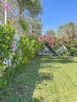Um jardim bem cuidado com cerca branca, grama verde exuberante e plantas floridas.
