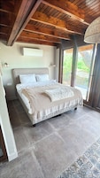 Quarto com uma cama grande, teto de madeira, janela e ar-condicionado fixado na parede.