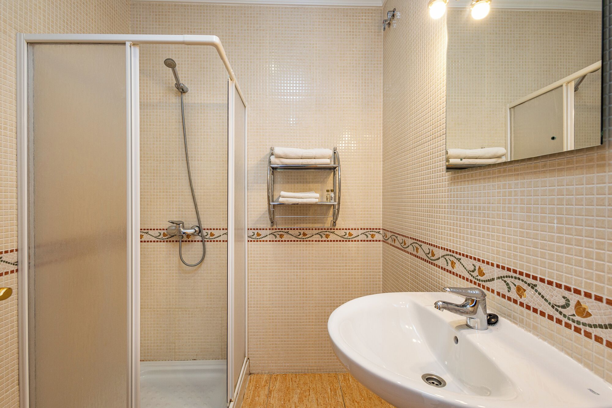Casa de banho com chuveiro, lavatório e suporte para toalhas.