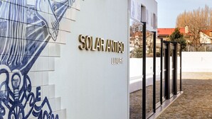 Um edifício com um letreiro que diz 'SOLAR ANIGO LUXURY' e uma parede de azulejos com desenhos abstratos.