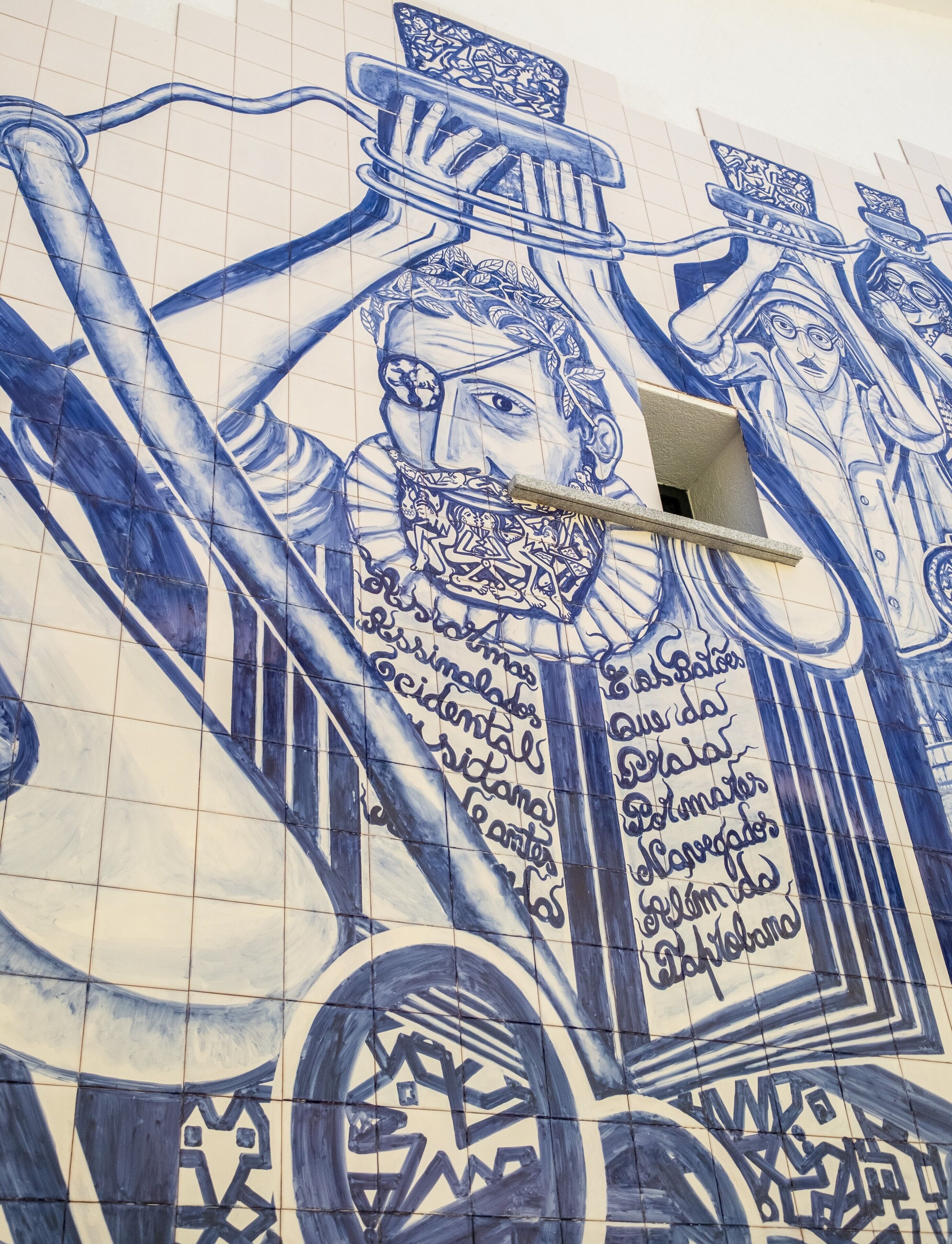 Parede azulejada com padrões e texto em azul.