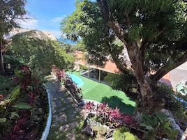 Um jardim exuberante com piscina, caminho de pedra e um gazebo.