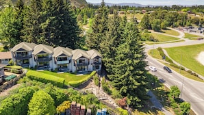 Um hotel com vários andares e varandas, rodeado por vegetação exuberante e com vista para montanhas.