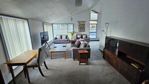 Uma sala de estar com sofá, televisão, mesa de madeira e um armário.