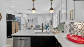 Cozinha moderna com ilha central, eletrodomésticos de aço inoxidável e iluminação pendente.