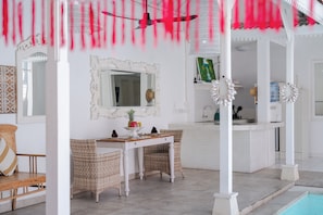 Um interior branco com área de jantar, cozinha e piscina.