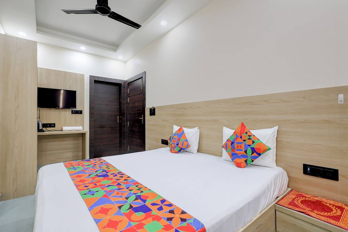 Quarto de hotel com uma cama, uma televisão, um guarda-roupa e uma mesa de cabeceira.