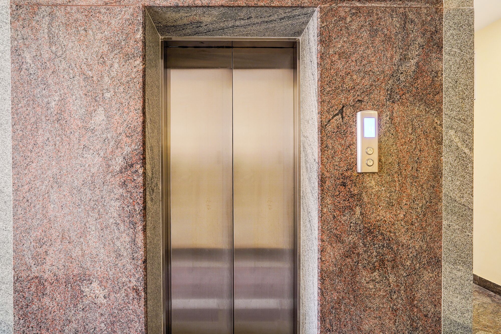 Um elevador com interior metálico e um painel de comando com botões.