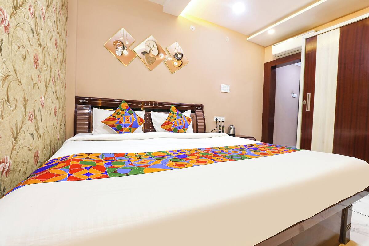 Quarto de hotel com cama, mesa de cabeceira, ar-condicionado fixado na parede e uma porta.
