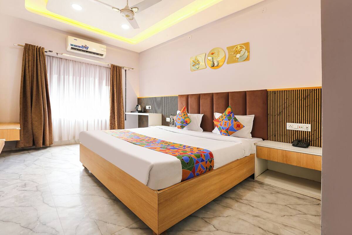 Quarto de hotel com cama, mesa de cabeceira e ar condicionado fixado na parede.