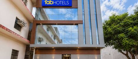 Fachada de hotel moderna com um destaque para a placa 'fabHOTELS', janelas amplas e uma entrada limpa.