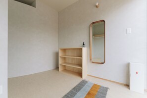 Quarto minimalista com uma prateleira de madeira, um espelho e um radiador.