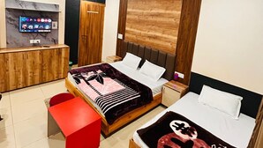 Quarto de hotel moderno com duas camas, uma televisão, um guarda-roupa de madeira e um banco vermelho.