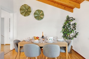 Uma área de refeições com uma mesa de madeira posta para dois, uma planta em vaso e arte decorativa na parede.