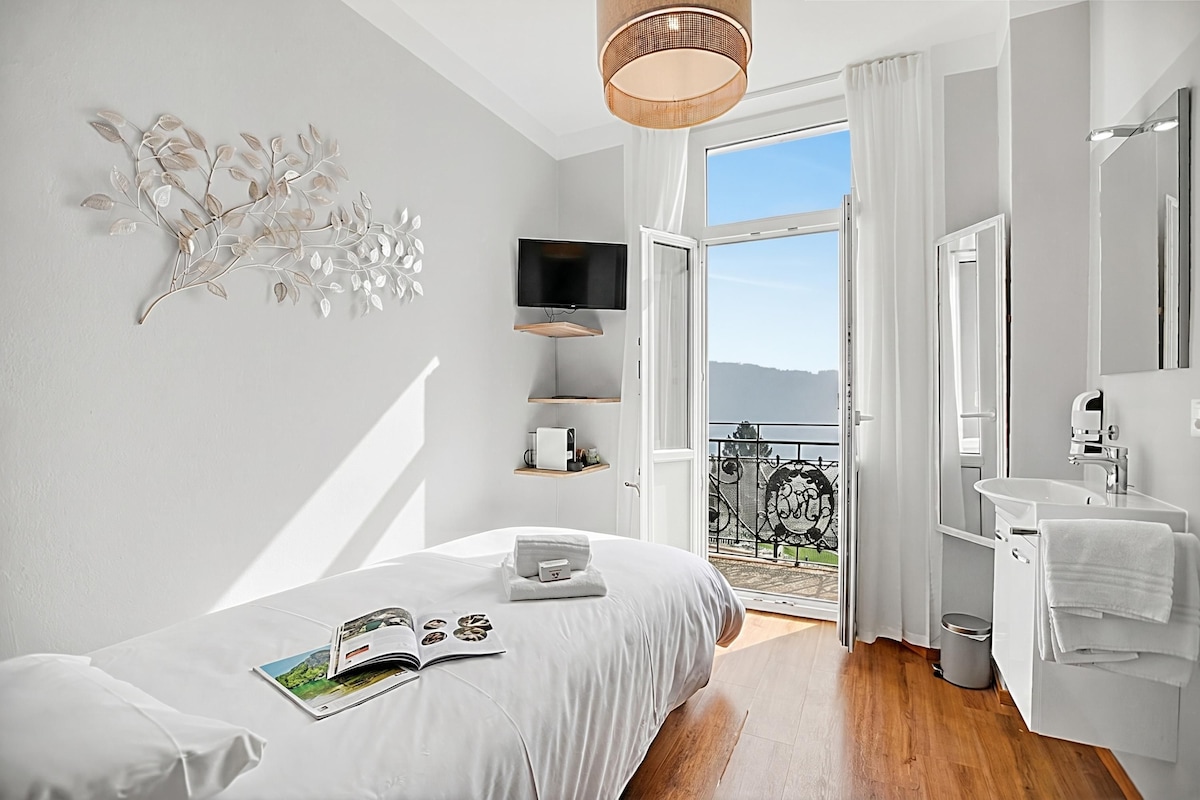 Quarto moderno com cama, televisão, varanda e banheiro.