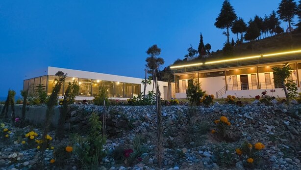 Um edifício moderno com grandes janelas e um jardim bem cuidado, com pedras e plantas.