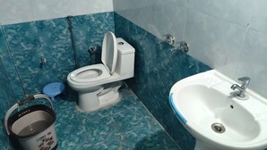 Um banheiro com vaso sanitário, pia e balde.