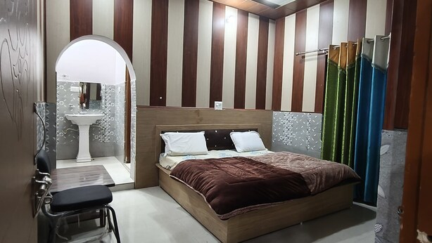 Quarto com cama, penteadeira com espelho, pia e uma cadeira.