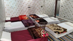 Quarto de hotel com quatro camas, cada uma com colchas de padrões diferentes.