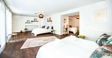 Quarto moderno com uma cama grande, uma mesa pequena, uma cadeira e uma mesinha de cabeceira.