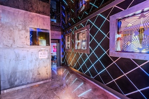 Um corredor com uma placa 'HOTEL', padrões geométricos nas paredes e piso de mármore.