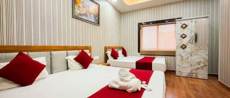 Quarto de hotel com duas camas, um espelho grande, um quadro na parede e piso de madeira.