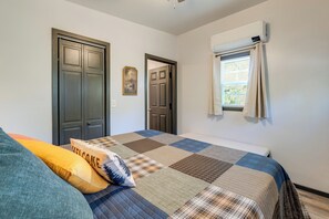 Quarto com cama, duas portas, janela com cortinas e ventilador de teto.