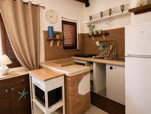 Cozinha compacta com bancada de madeira, forno embutido, pia e geladeira branca.