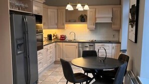 Cozinha moderna com ilha central, geladeira e mesa de jantar com cadeiras.