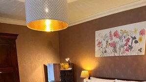 Quarto com cama, mesas de cabeceira, cômoda, abajur e um quadro na parede.