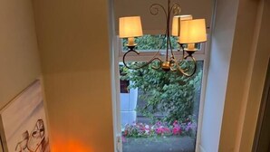 Quarto de canto com janela, uma mesa com abajur e uma escada.