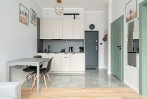 Cozinha moderna com armários brancos, bancada cinza e área de jantar com mesa e cadeiras.