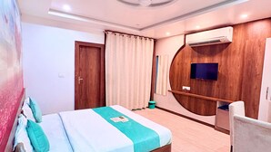 Quarto de hotel com cama, televisão, escrivaninha e cadeira.